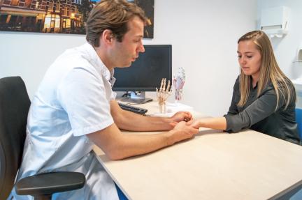Arts onderzoekt hand en pols patiënt